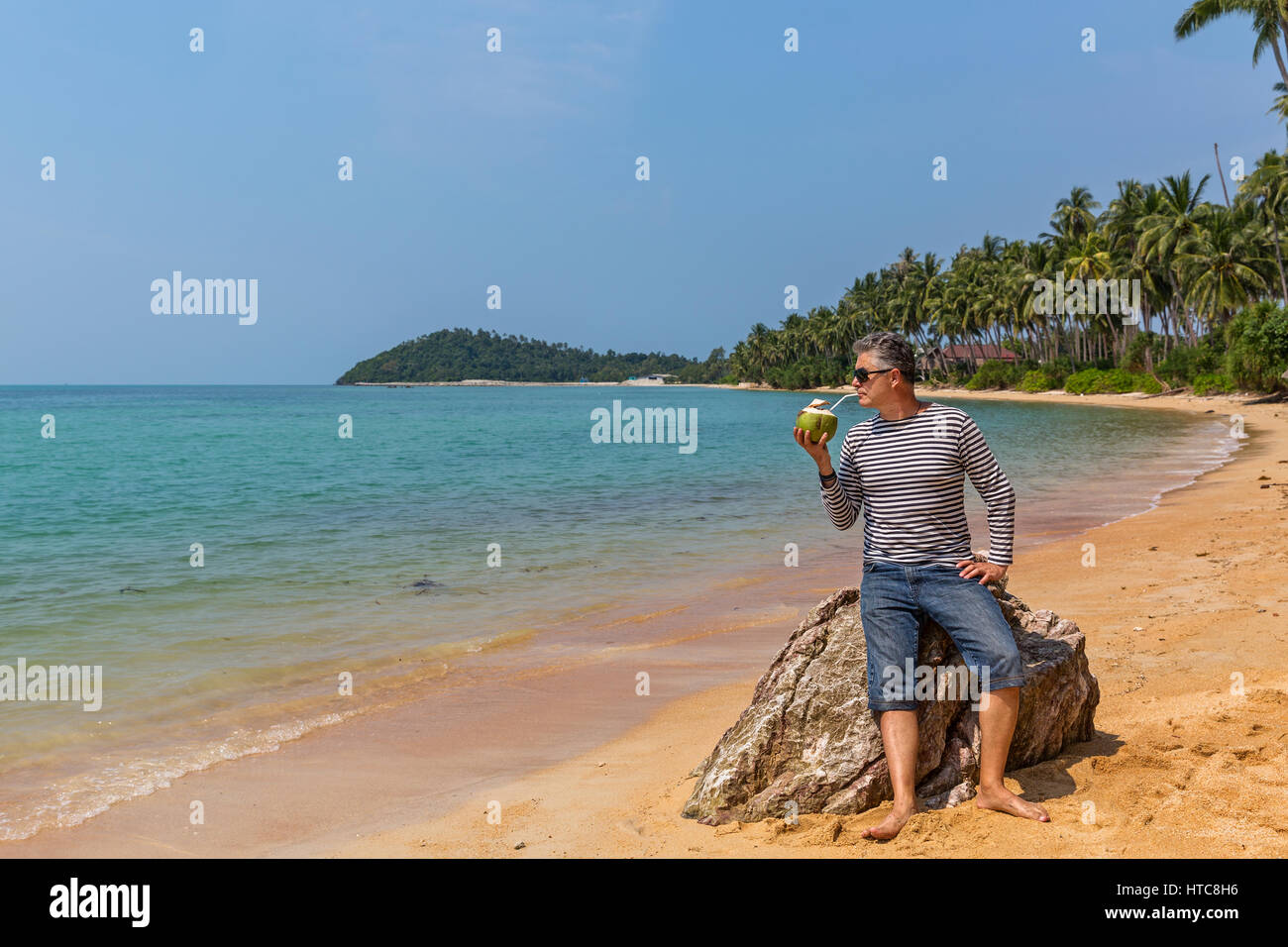 Man on the beach drinking fresh coconut juice Stock Photo - Alamy