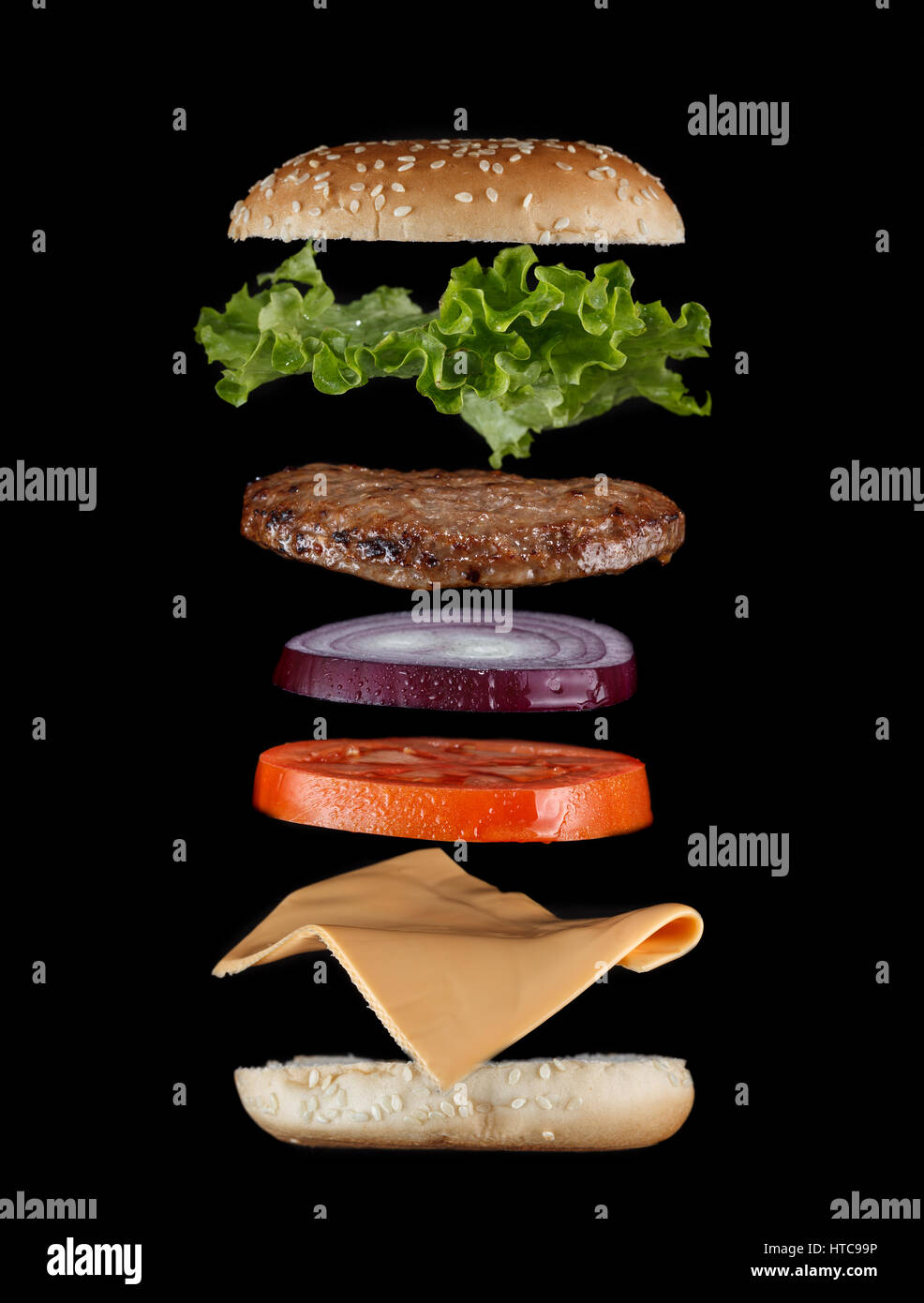Stacked juicy hamburger ingredients isolated on black. Fast food menu ...