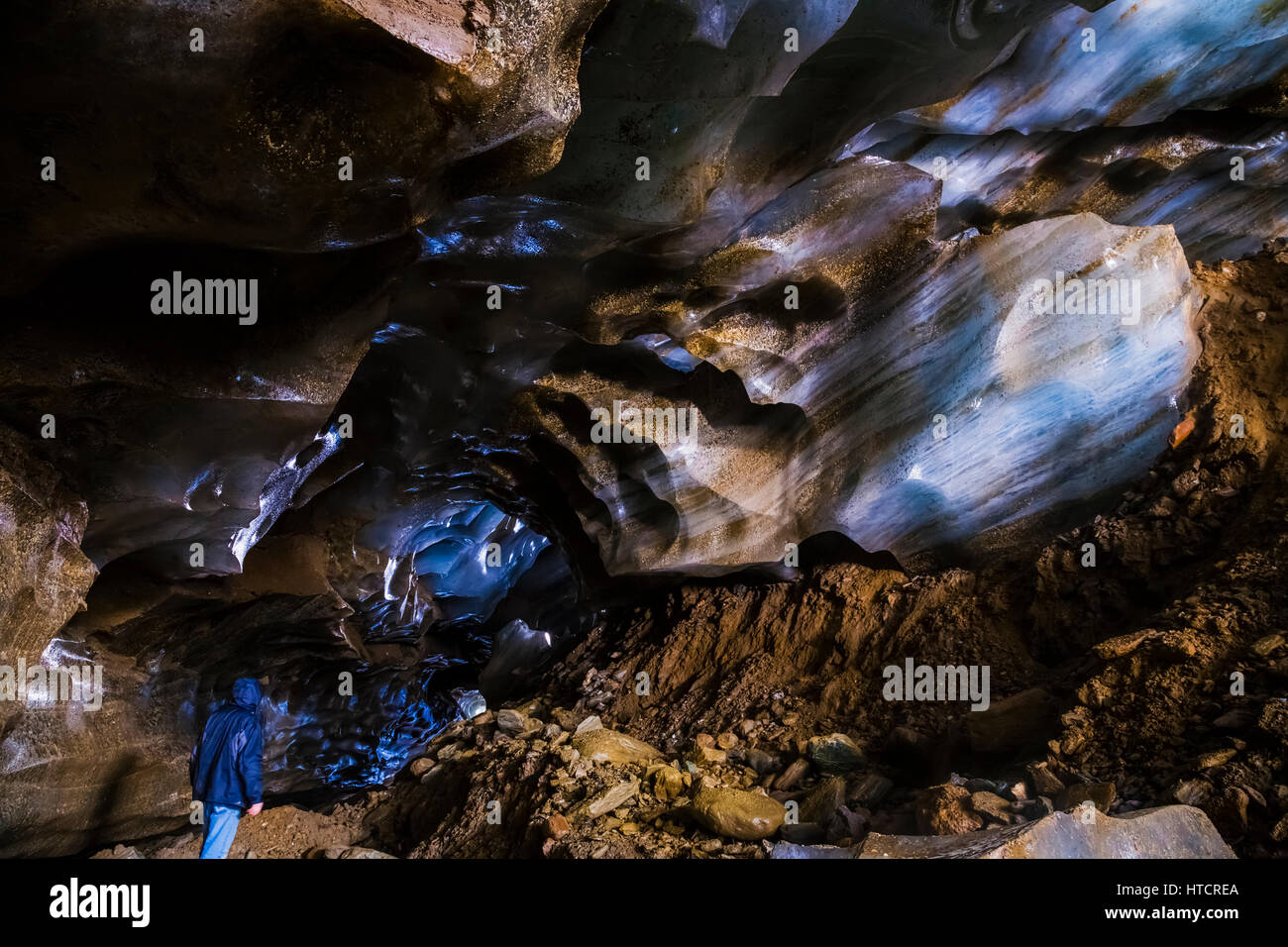 A man stands inside a massive ice cave within Castner Glacier in the ...