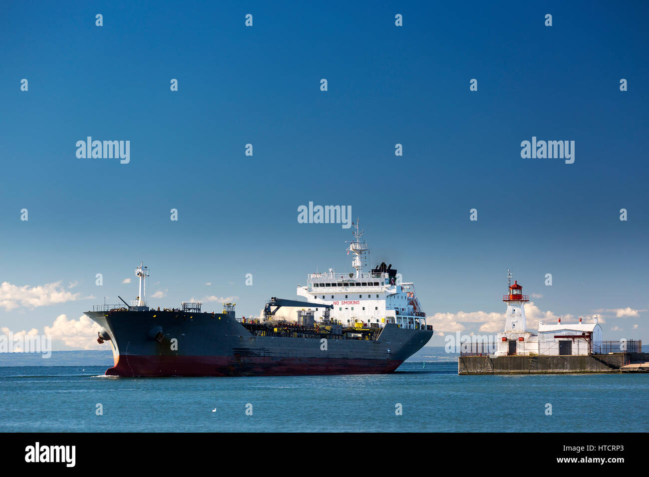 Large laker ship in water next to white and red lighthouse on at the ...