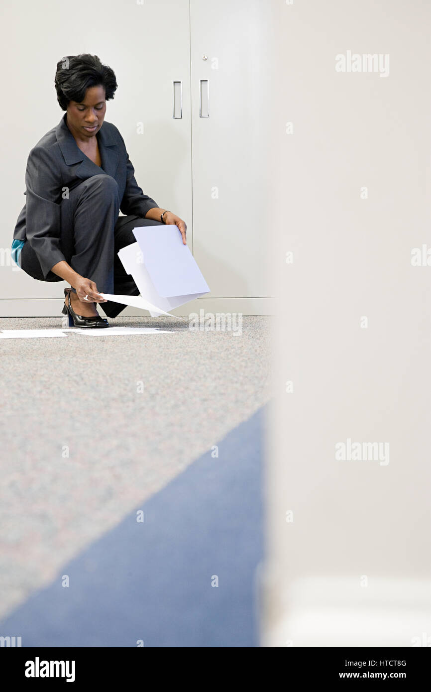 Businesswoman picking up paper Stock Photo - Alamy