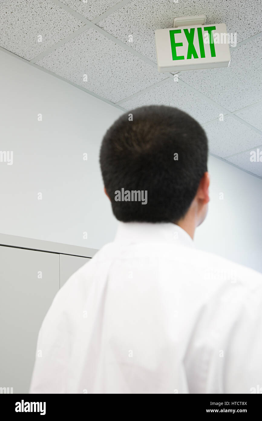 Office worker looking at exit sign Stock Photo - Alamy