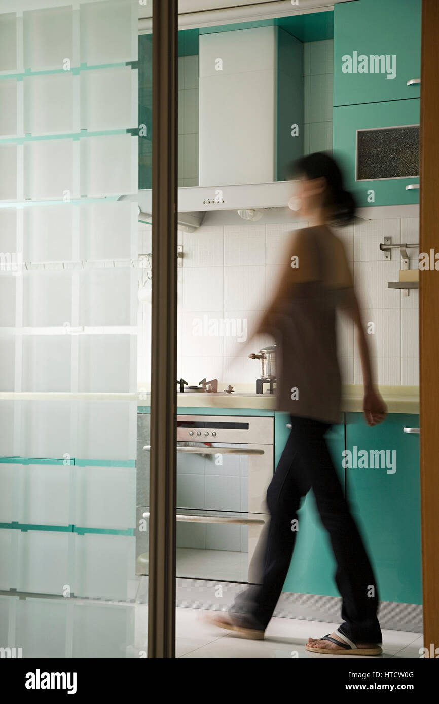 Young woman walking in a kitchen Stock Photo - Alamy