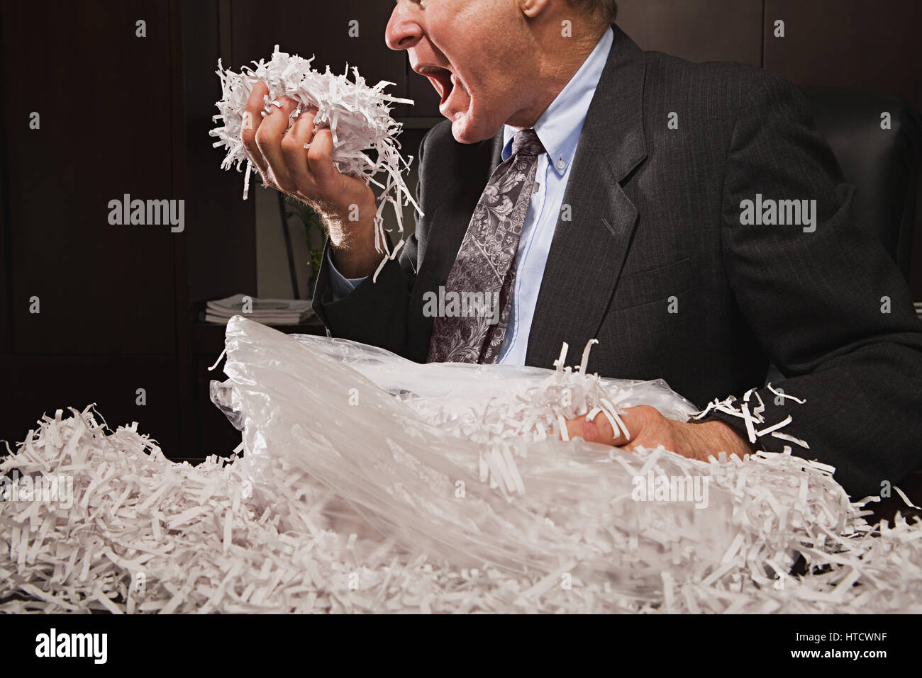 Mature businessman playing with paper shreddings Stock Photo - Alamy