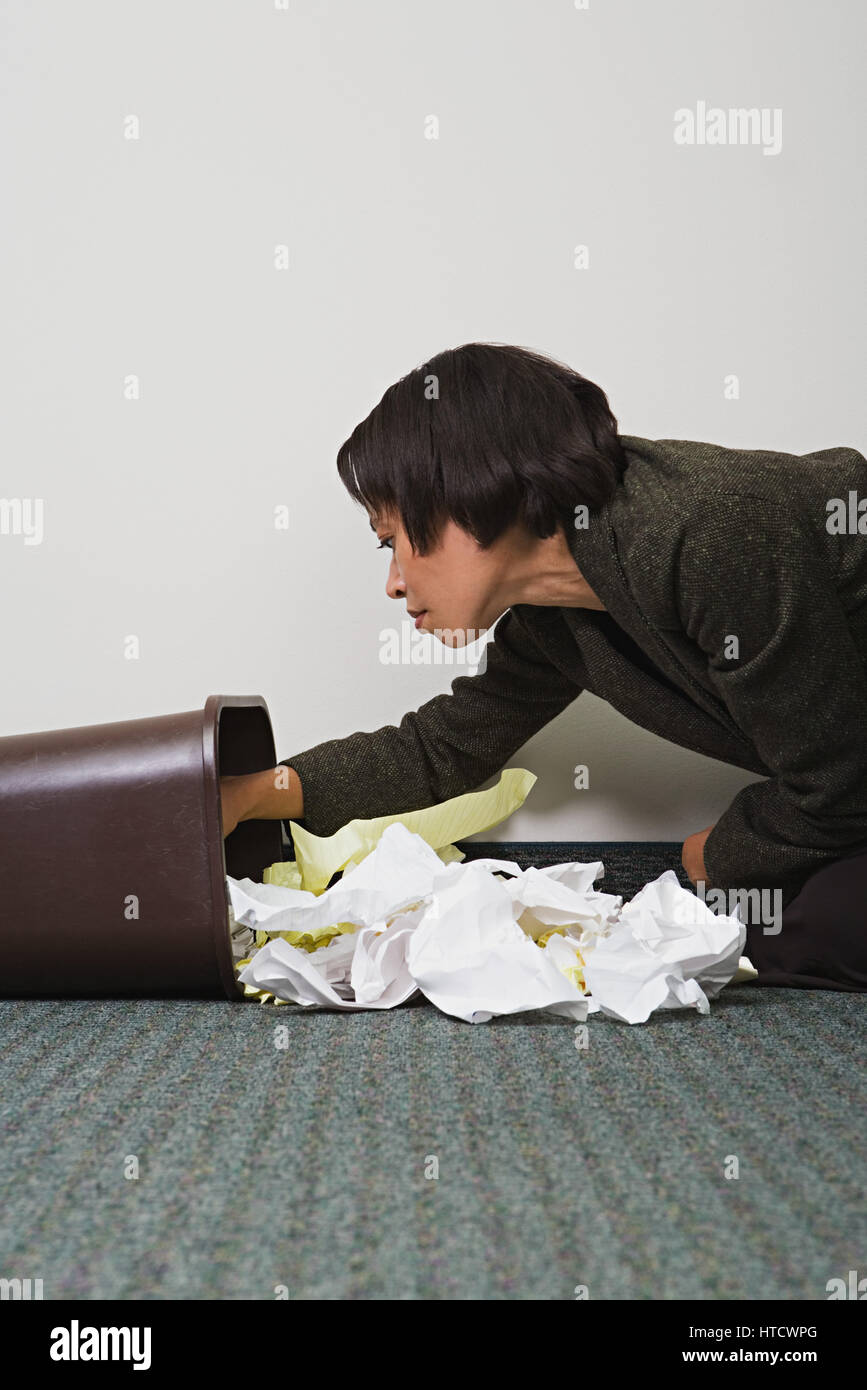 Businesswoman searching through rubbish bin Stock Photo - Alamy