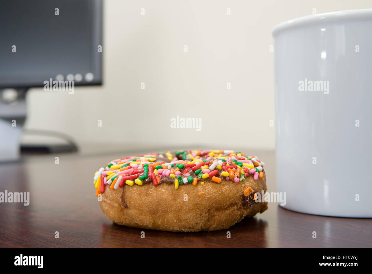 Coffee cup and doughnut on desk Stock Photo - Alamy