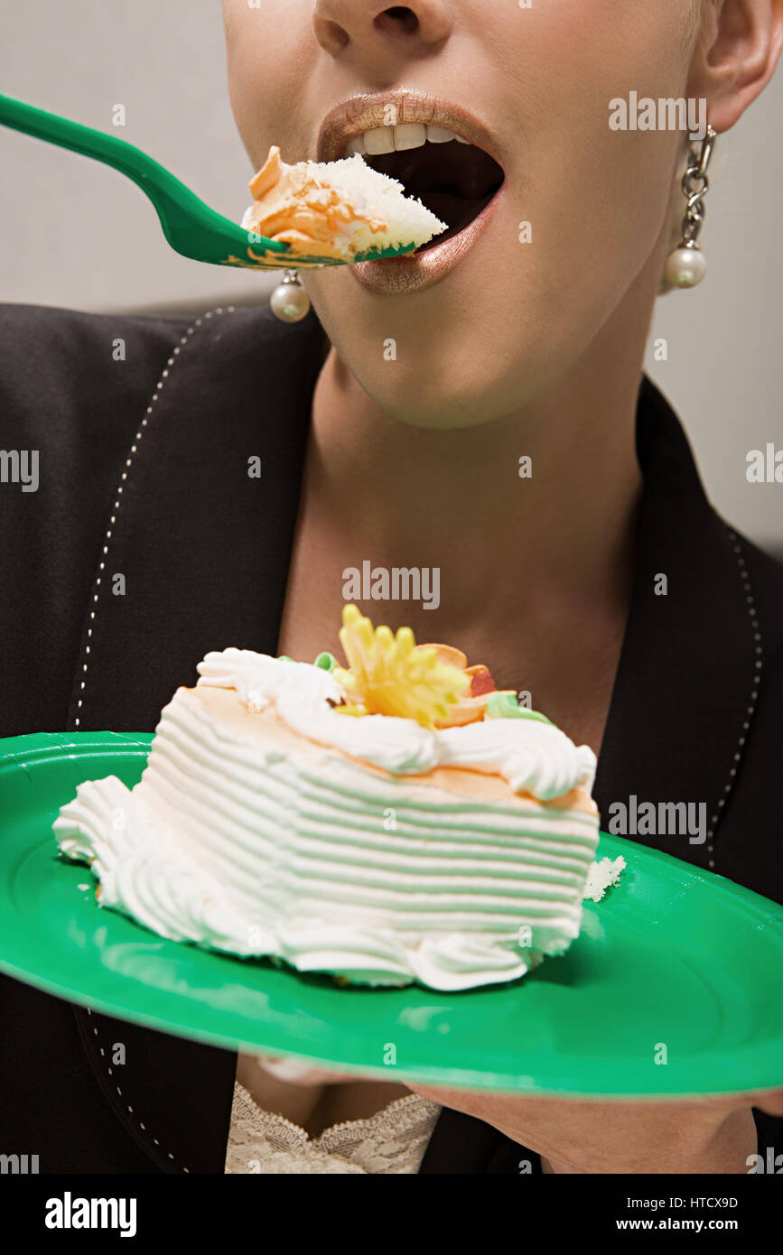 Businesswoman eating cake Stock Photo - Alamy
