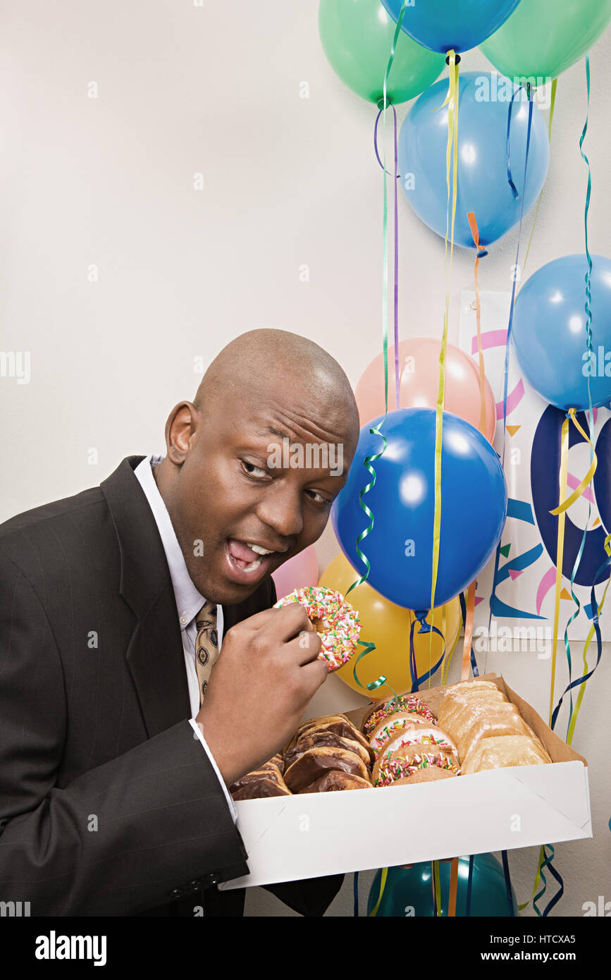Businessman secretly eating doughnuts Stock Photo - Alamy