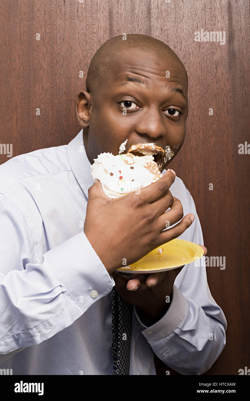 Businessman eating cake Stock Photo - Alamy