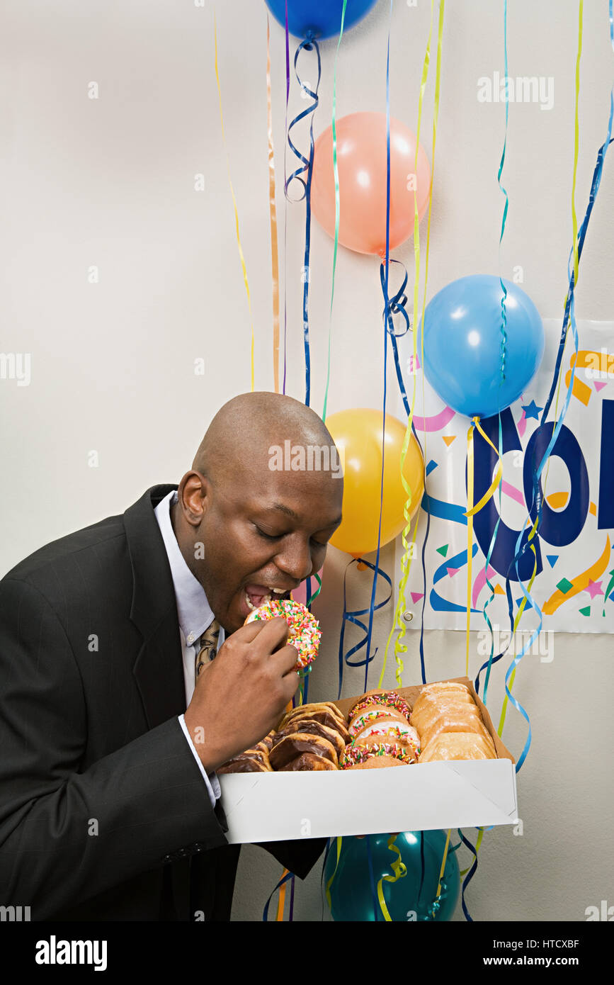 Businessman secretly eating doughnuts Stock Photo - Alamy