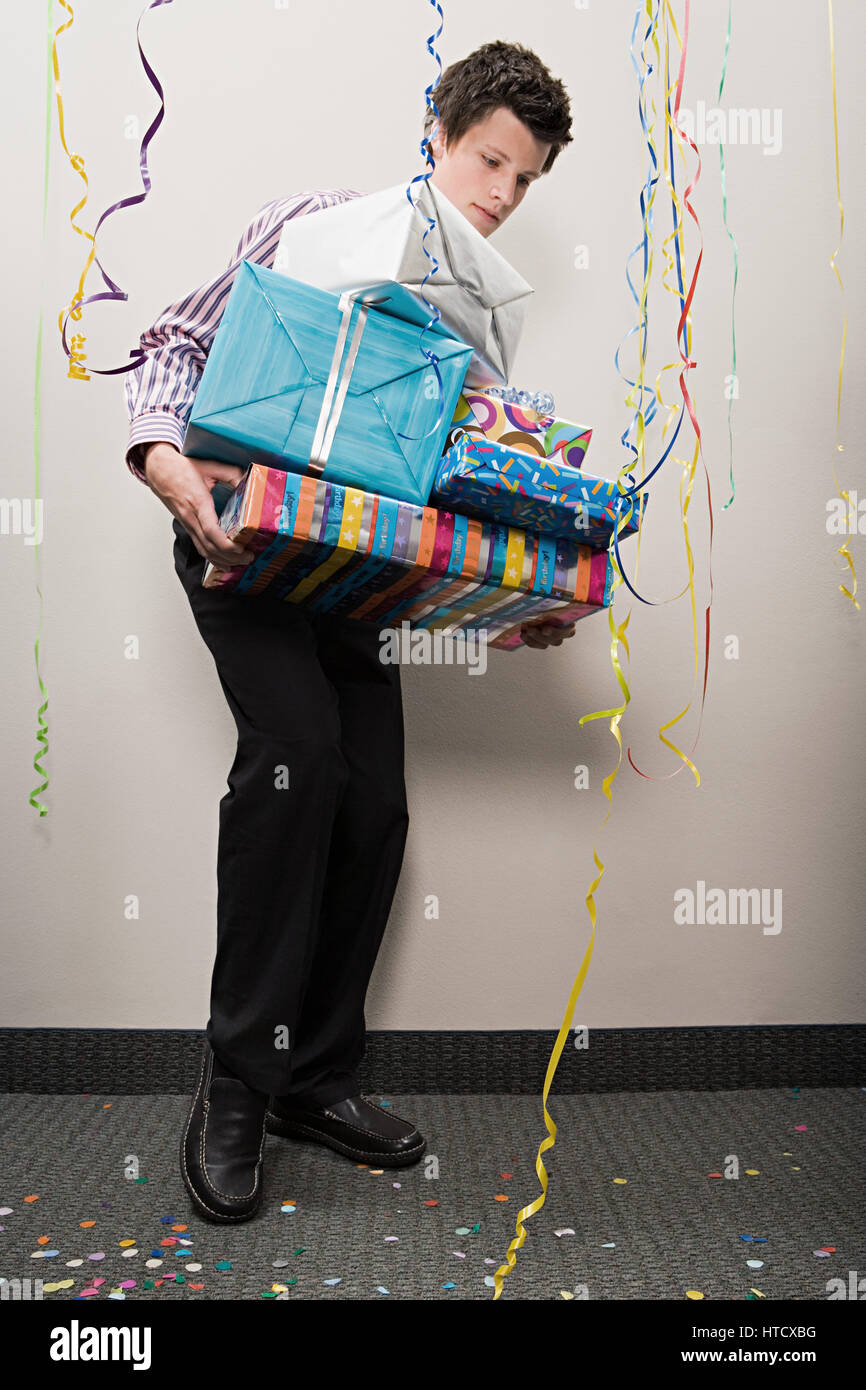 Businessman struggling with pile of presents Stock Photo - Alamy