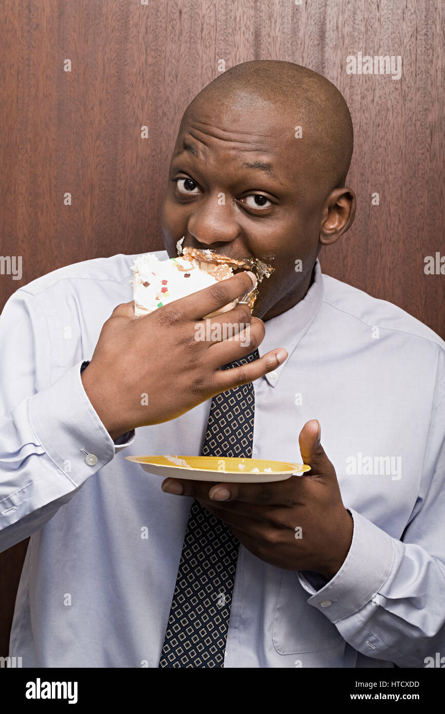 Businessman secretly eating cake Stock Photo - Alamy