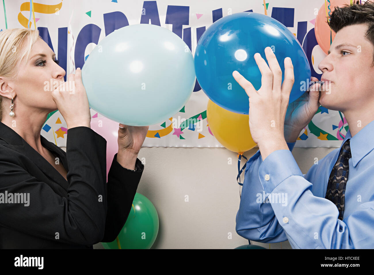 Two office workers blowing up balloons Stock Photo - Alamy