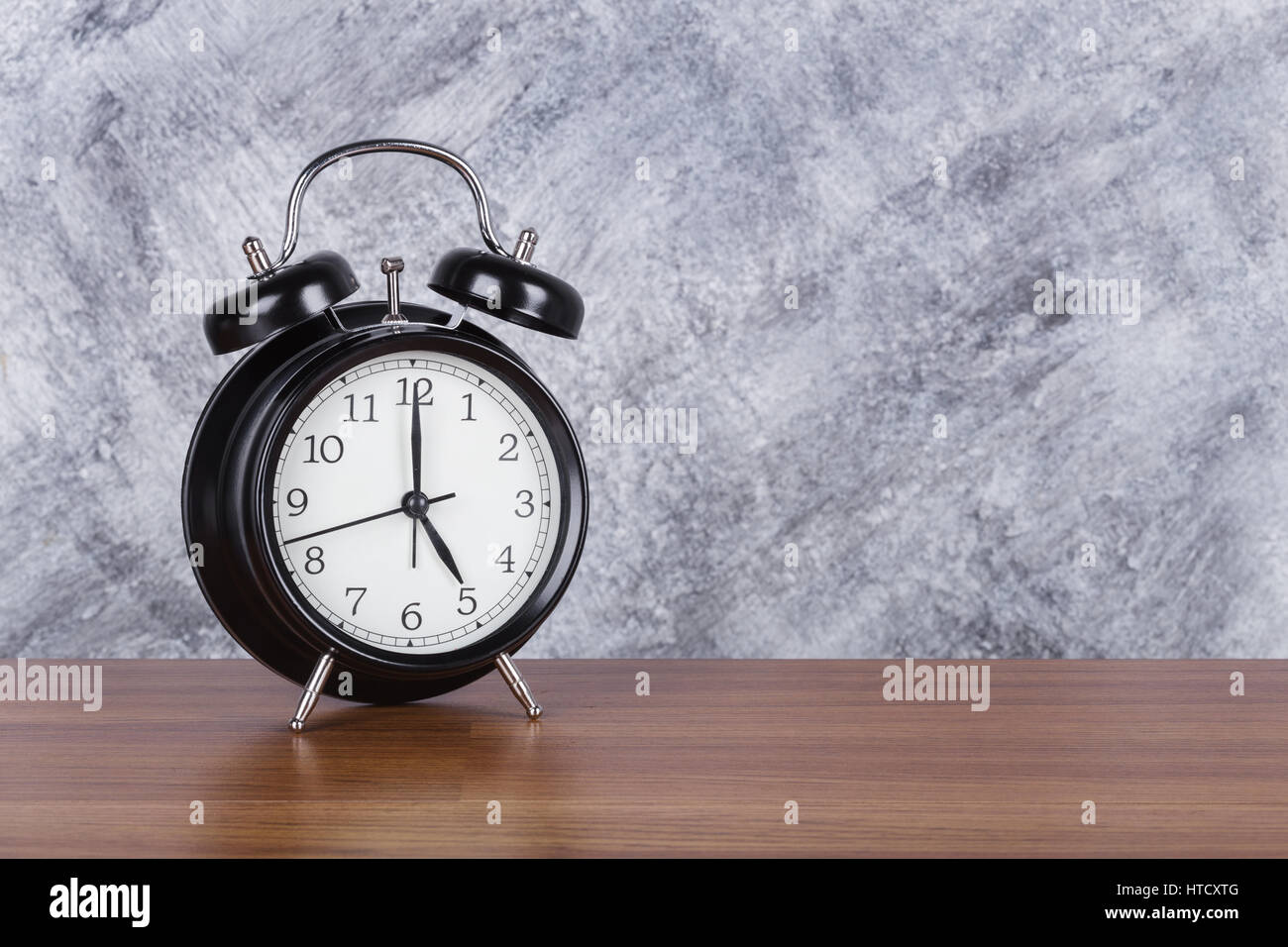 5 o'clock vintage clock on wood table and concrete wall background ...