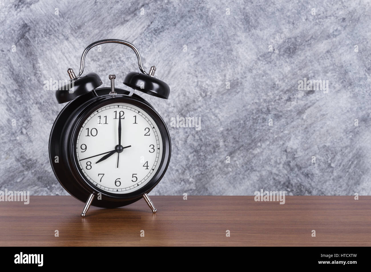 8 o'clock vintage clock on wood table and concrete wall background ...