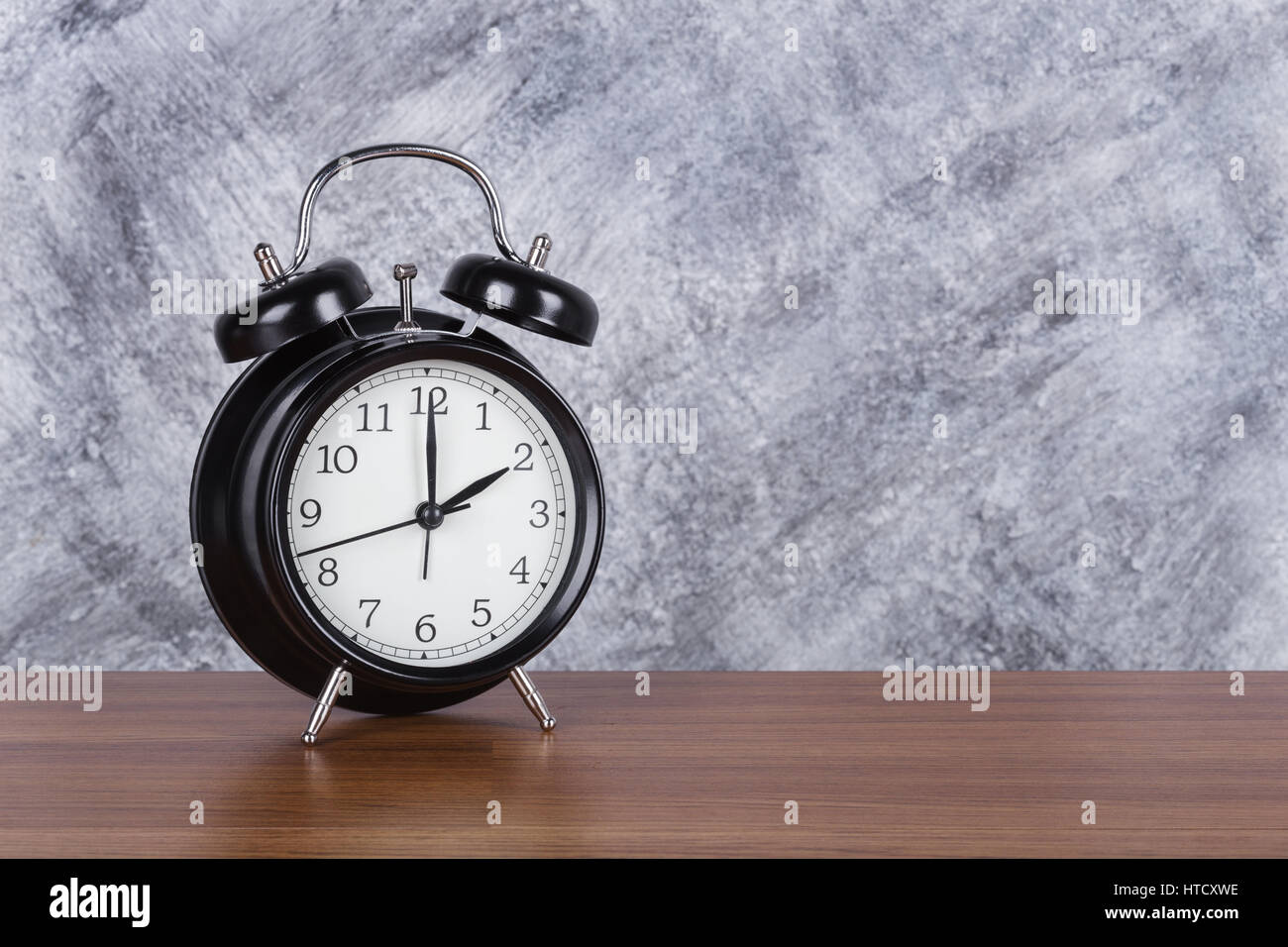 2 o'clock vintage clock on wood table and concrete wall background ...