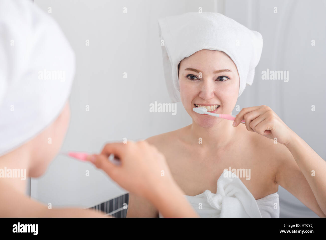 woman in bath towel brushing teeth with mirror in the bathroom Stock ...