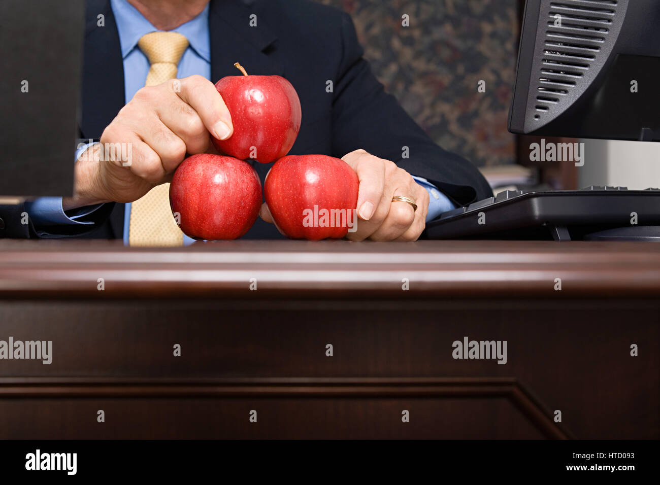 Businessman balancing apples on desk Stock Photo - Alamy