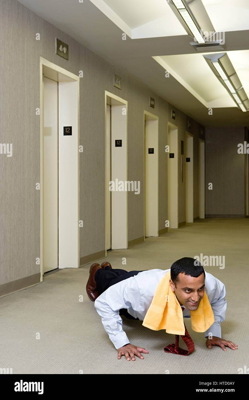 Office worker doing push ups in corridor Stock Photo - Alamy