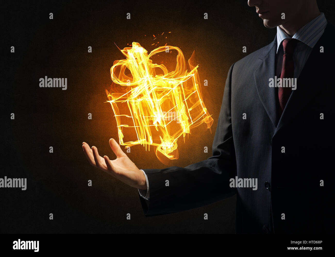 Glowing fire gift box icon in palm on dark background Stock Photo - Alamy