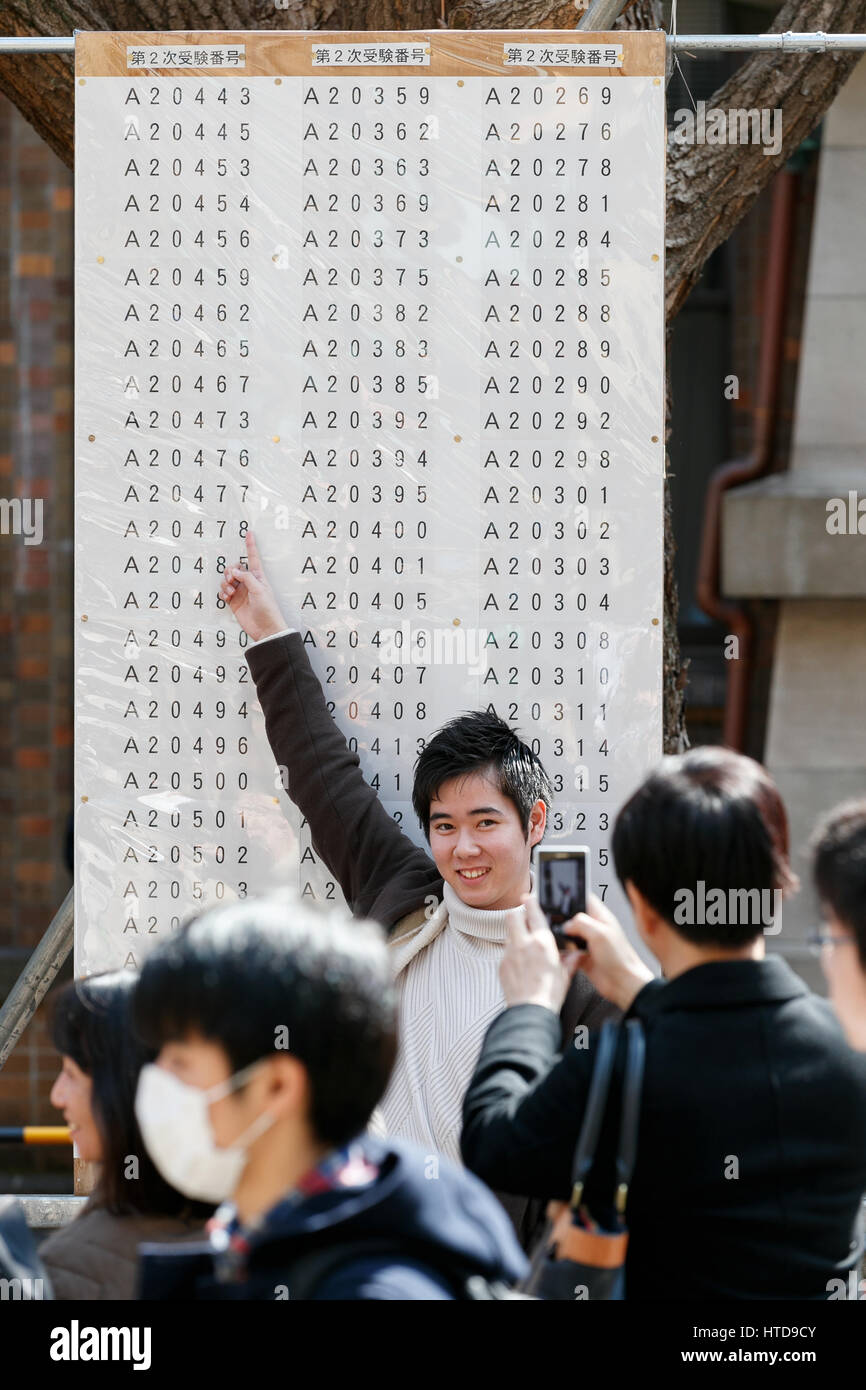 A Japanese student points his exam number on the list at the University ...