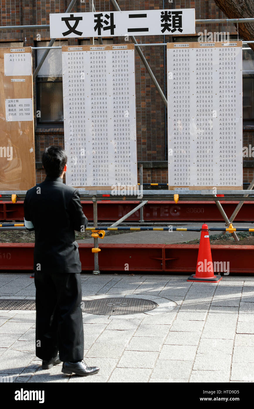 A Japanese student looks for his exam number on the list at the ...