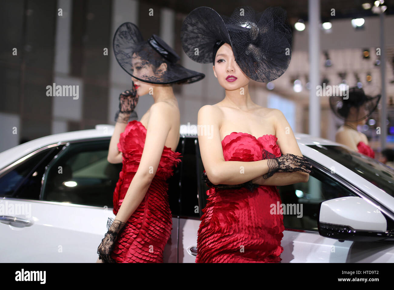 Weifang, China. 9th Mar, 2017. Car models wearing red dresses stand in ...