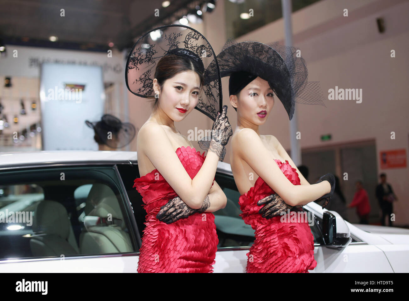 Weifang, China. 9th Mar, 2017. Car models wearing red dresses stand in ...