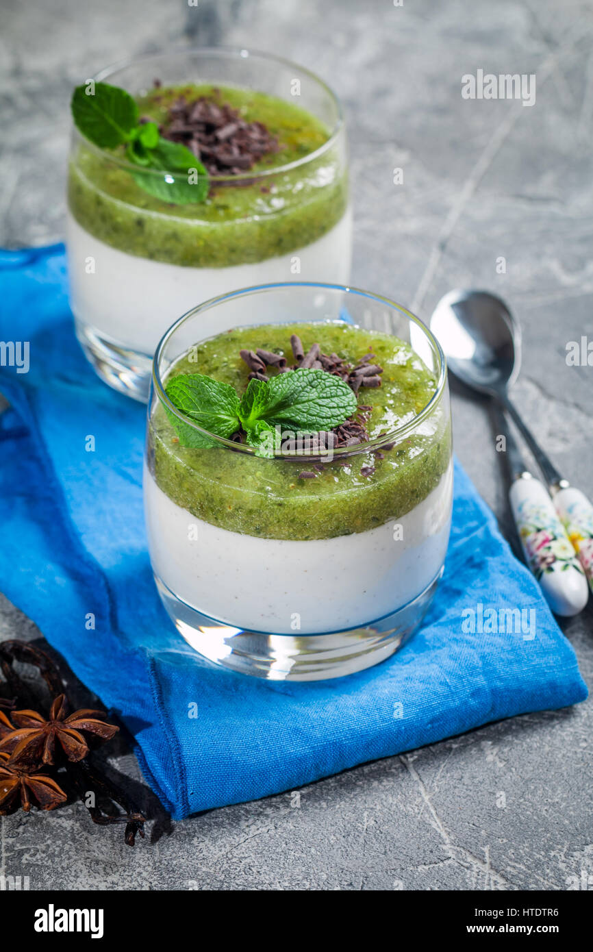 Fruit dessert green panna cotta with mint in a glass over grey ...