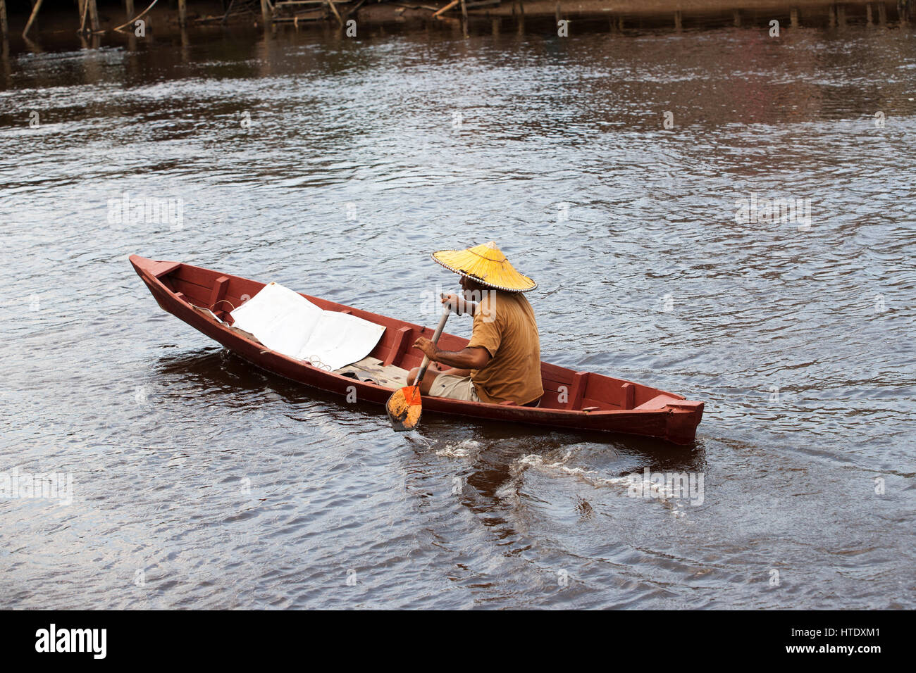 One asian man rowing his little boat with a small paddle on a brown ...