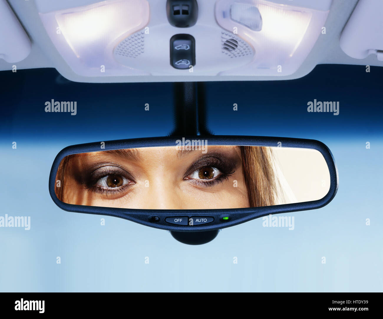 Young woman sits on driver's seat and Looks in the rear-view mirror ...