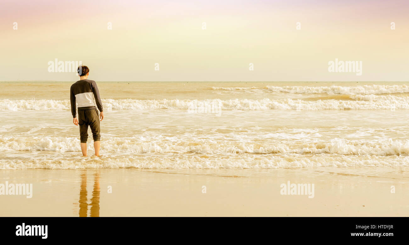 Young man watching the sea on the beach Stock Photo - Alamy