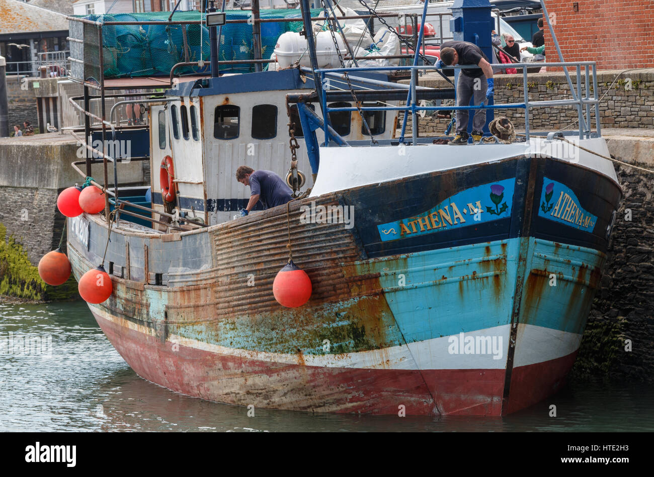 Rusty trawler or fishing boat moored in Padstow harbour. The crew are ...