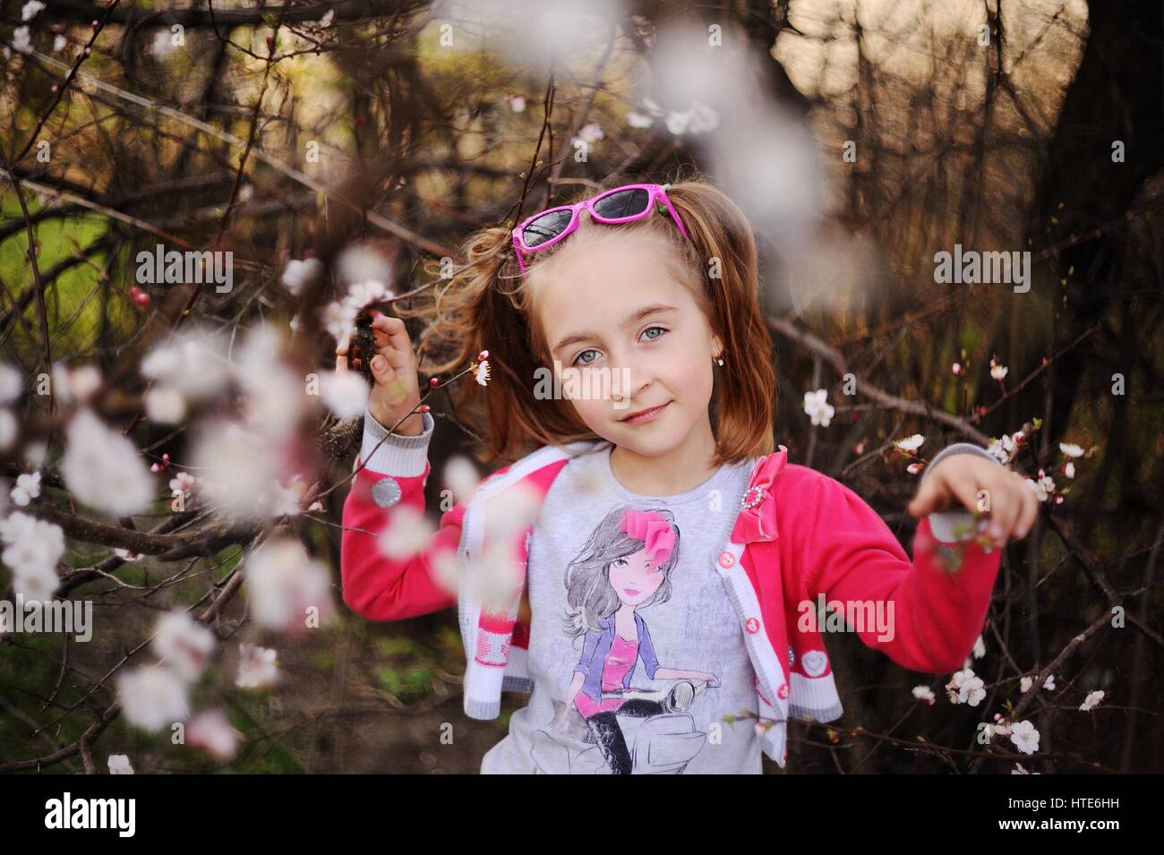 Baby girl in a flowering tree against a background of spring weather ...