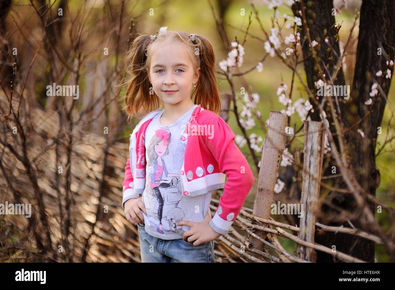 Baby girl in a flowering tree against a background of spring weather ...