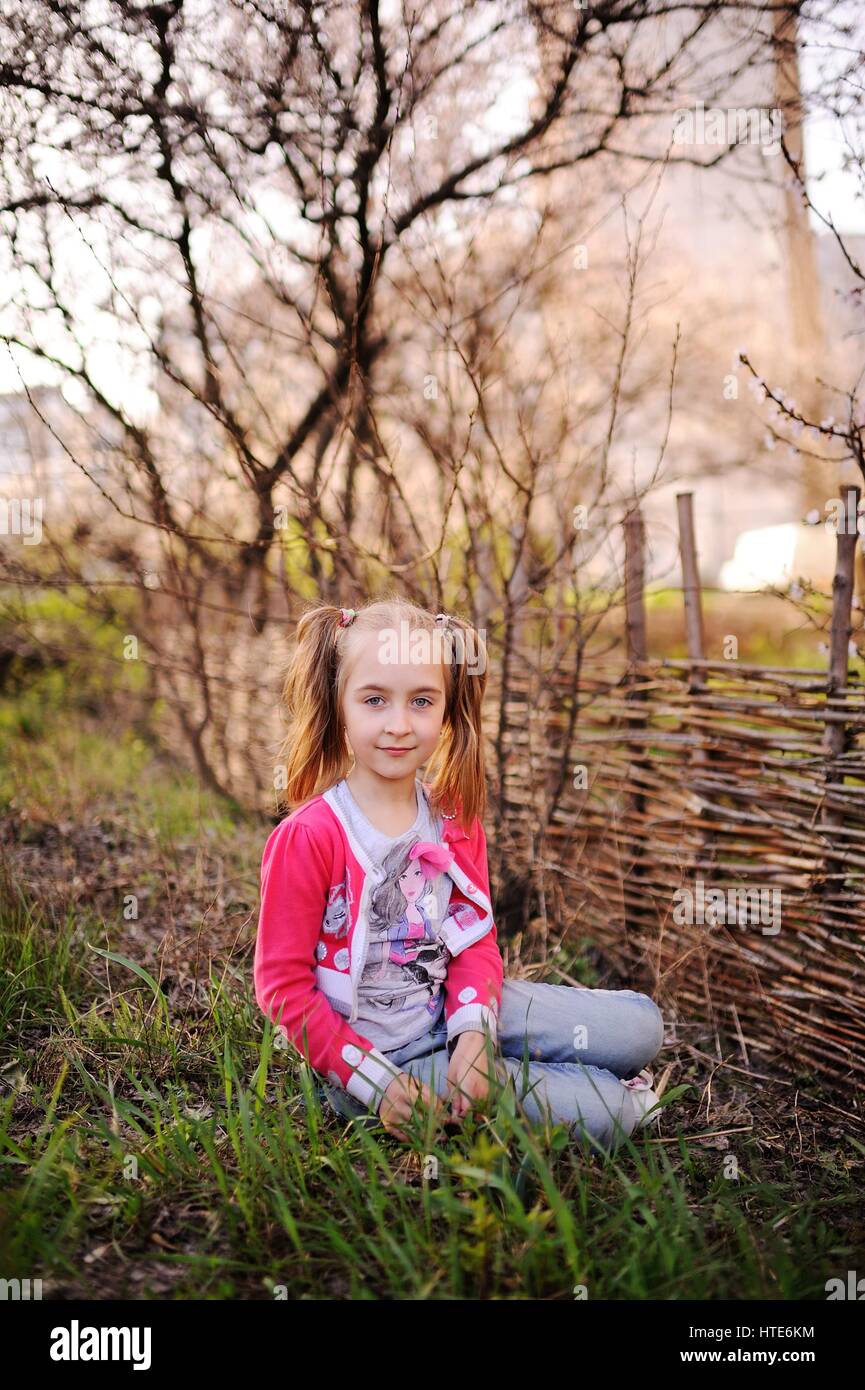 Baby girl in a flowering tree against a background of spring weather ...