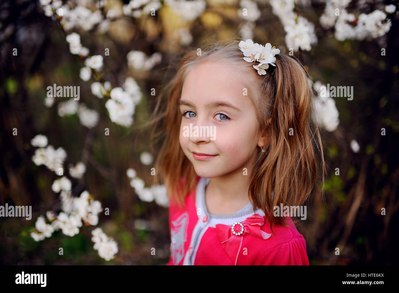 Baby girl in a flowering tree against a background of spring weather ...