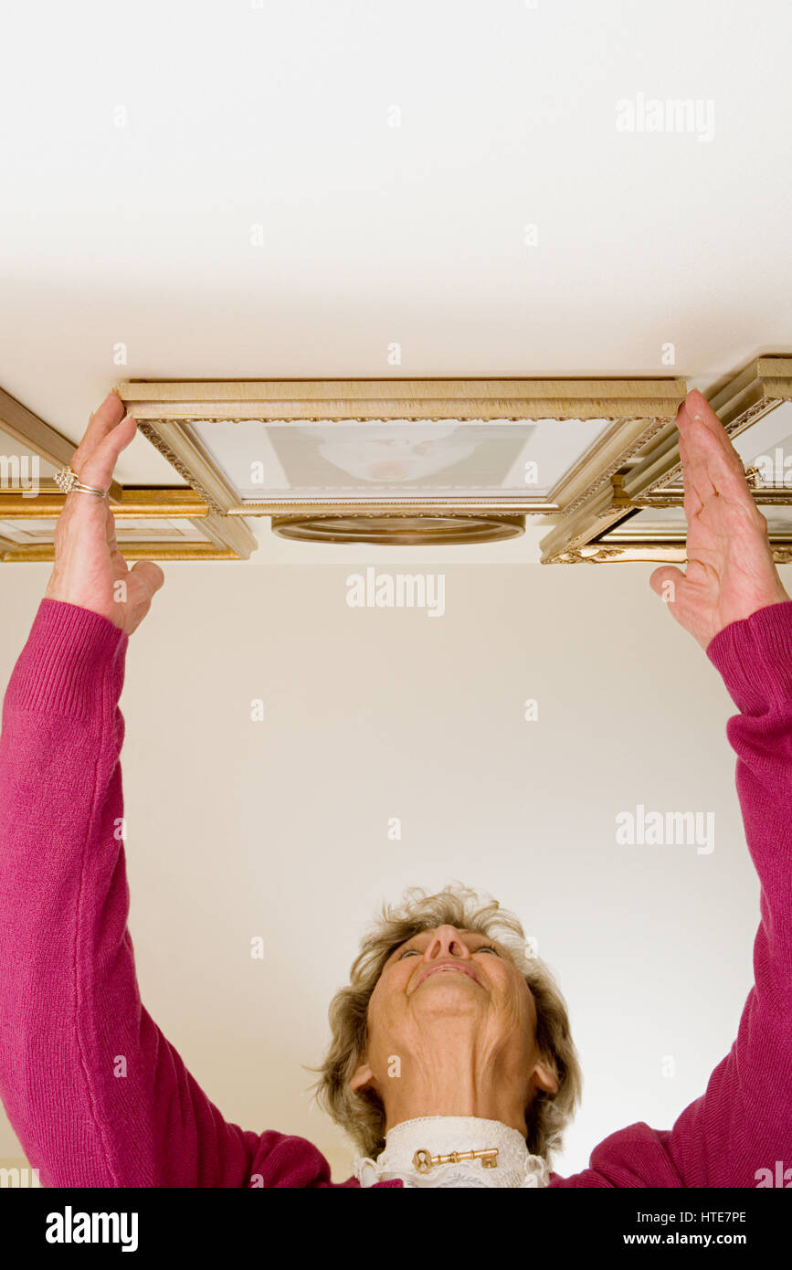 Woman adjusting picture frames Stock Photo - Alamy