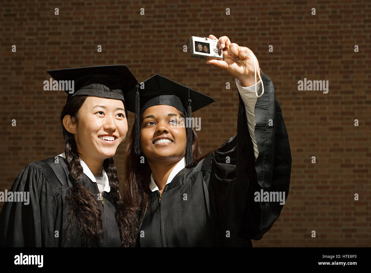 Two female graduates taking a photograph Stock Photo - Alamy