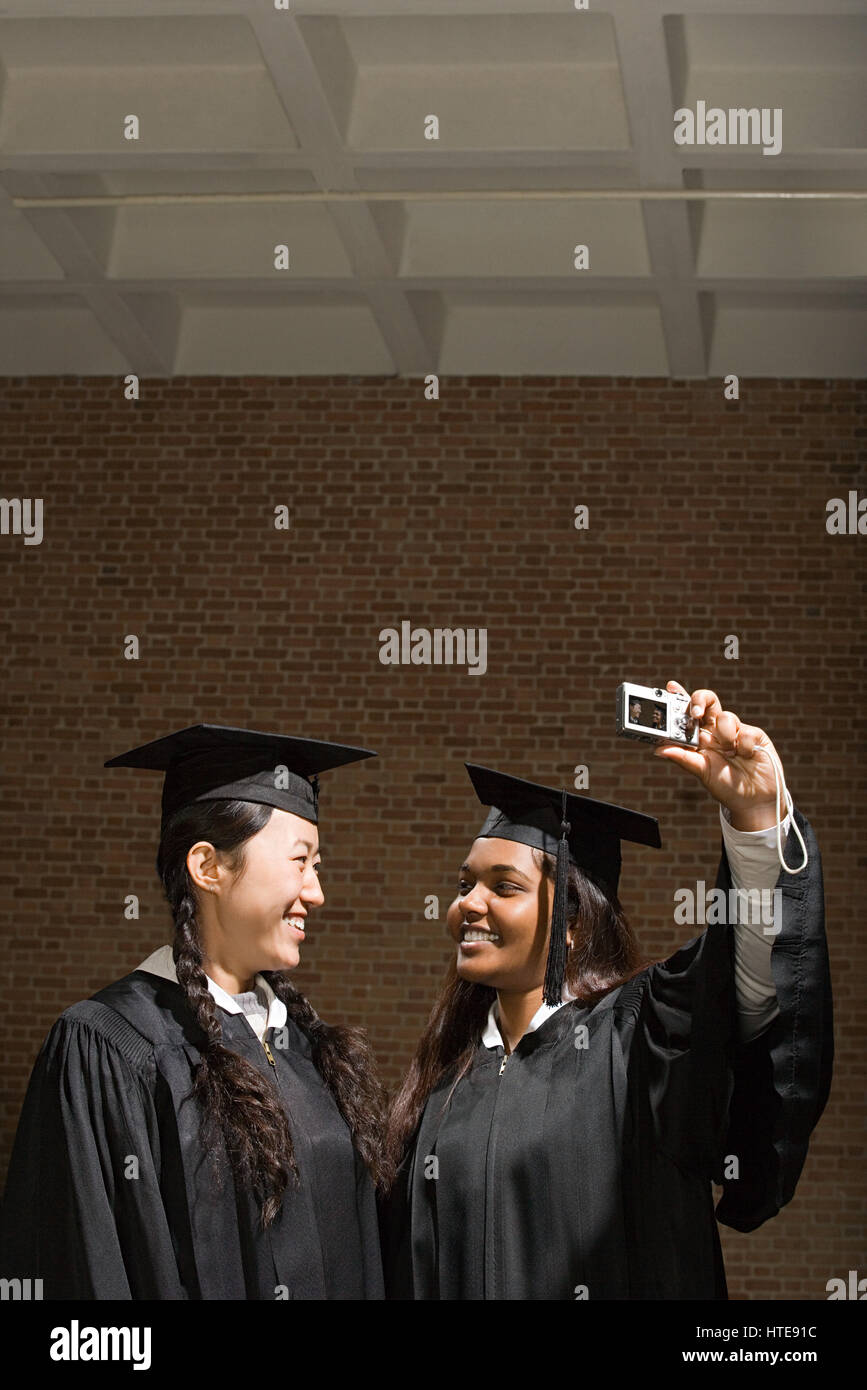 Two female graduates taking a photograph Stock Photo - Alamy