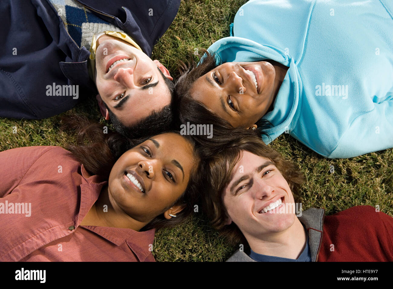 Four students lying down outdoors Stock Photo - Alamy