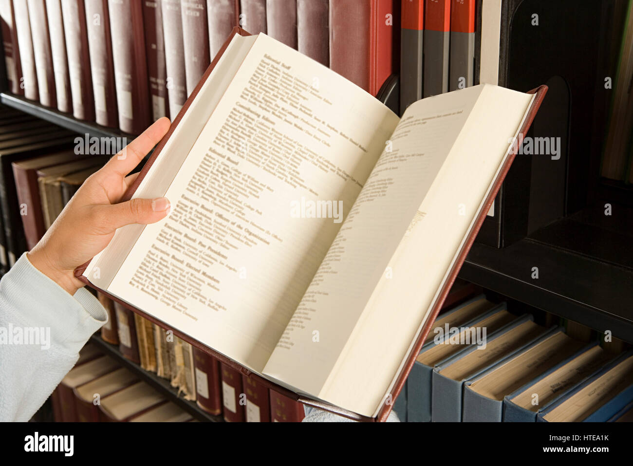 Female student reading a book in the library Stock Photo - Alamy