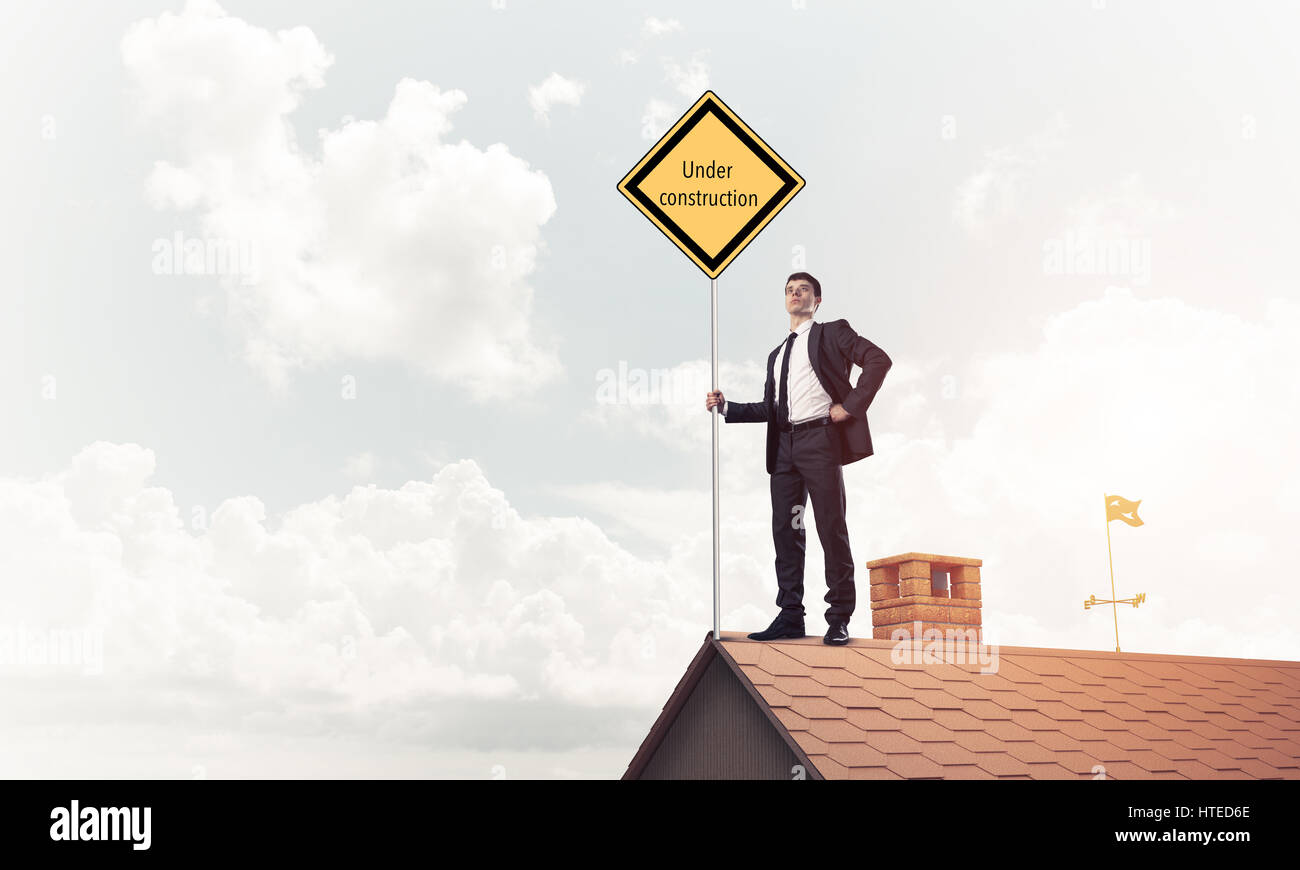 Man holding safety sign indicating under construction notice. Mixed ...