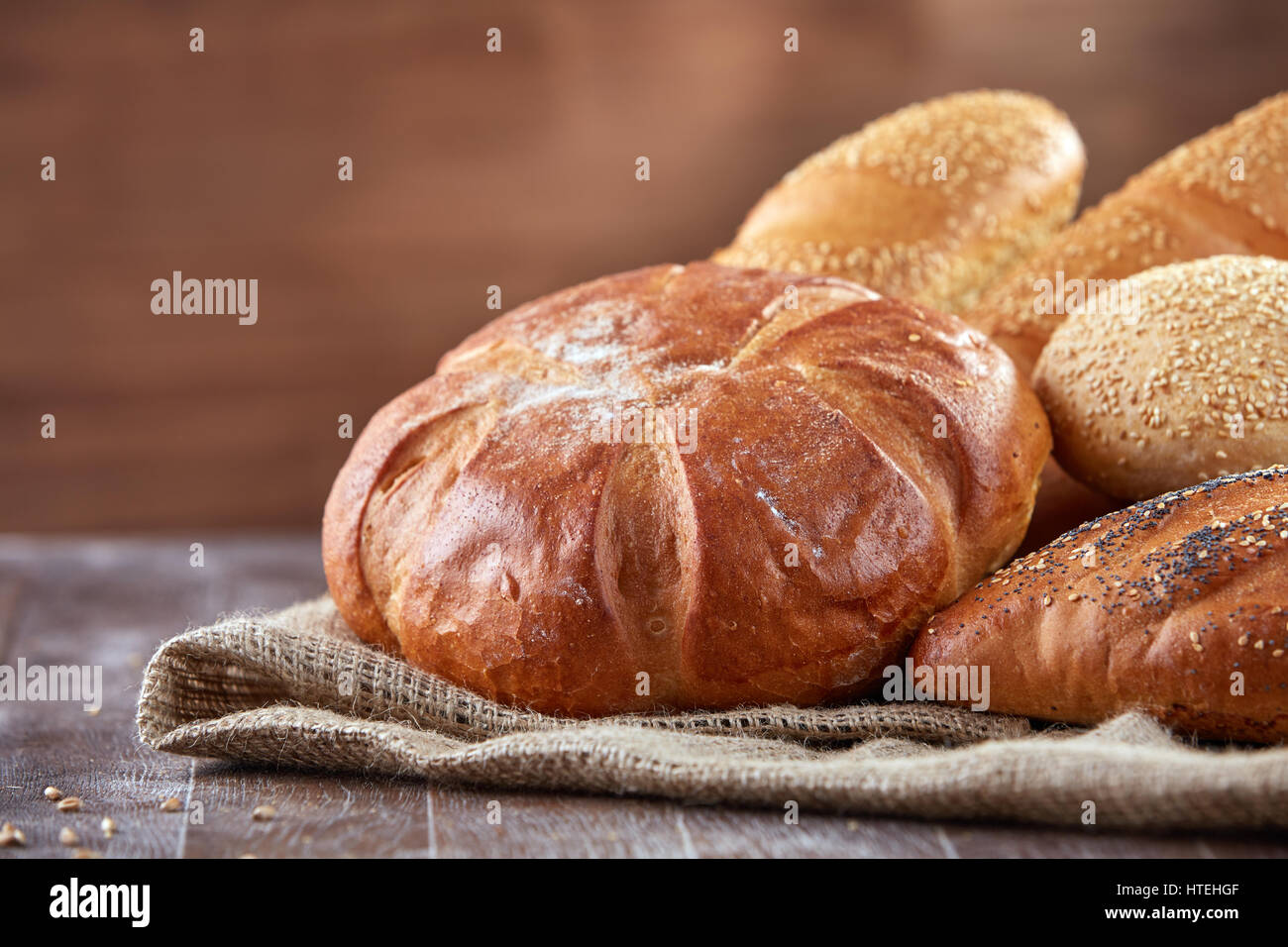 Fresh bread on a cloth linen with brown background on the wooden table ...