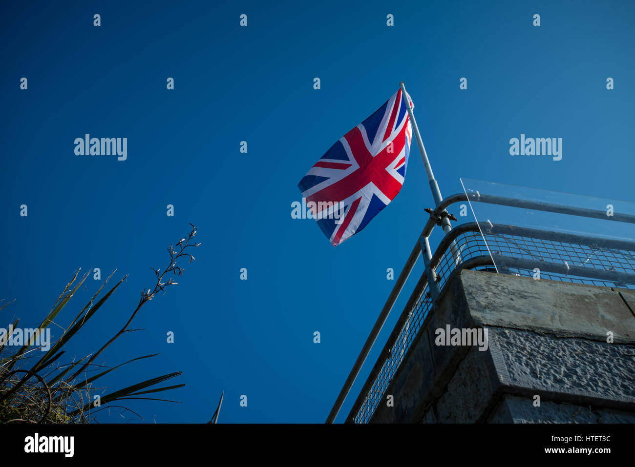 A union jack flag flutters in the breeze against a clear blue sky Stock ...