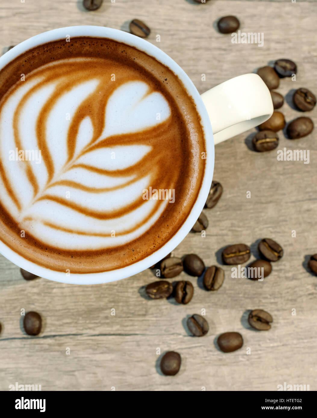 Cup of hot drink with coffee beam on wooden table Stock Photo - Alamy