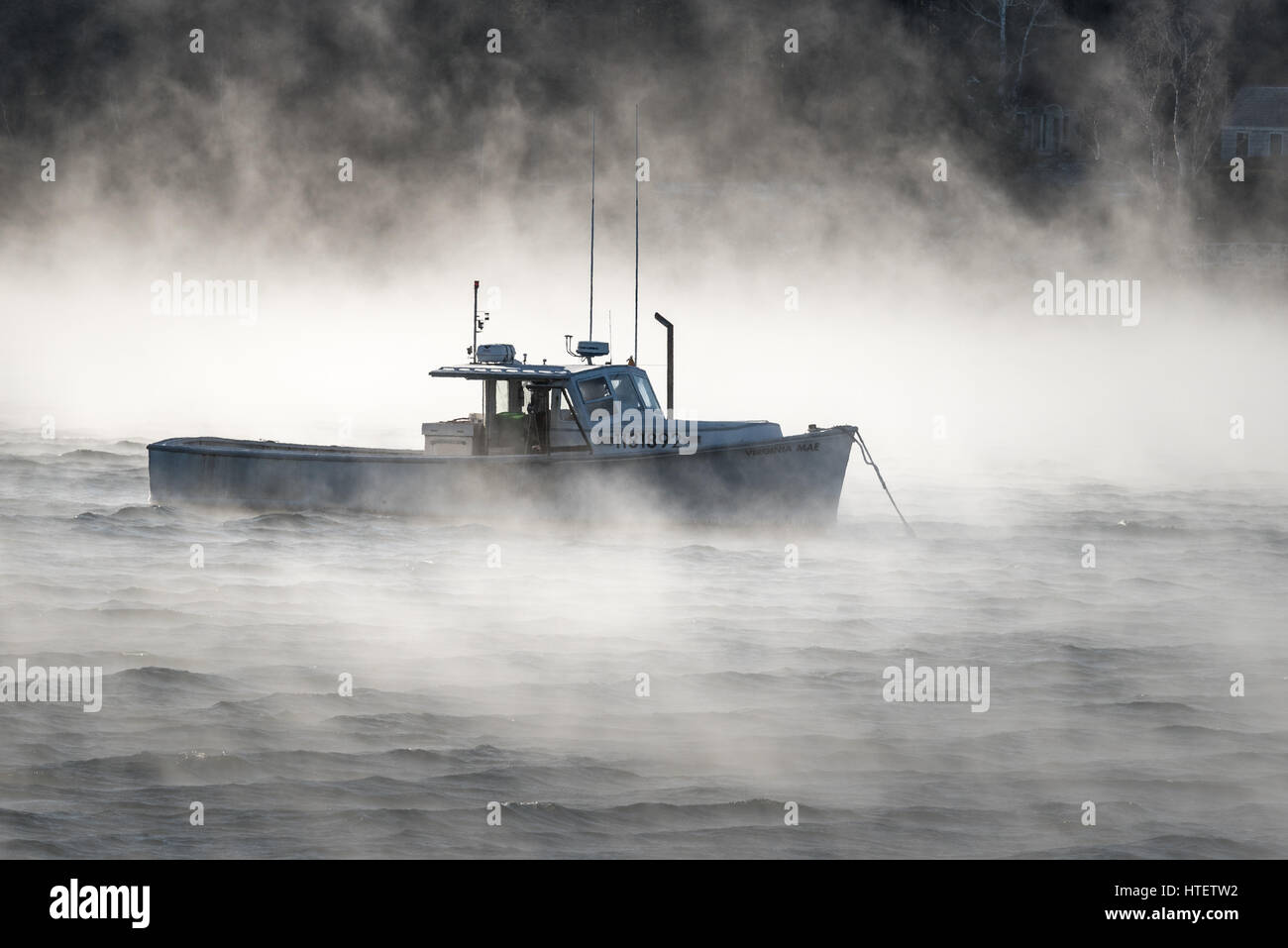 Sea smoke rises from the surface and surrounds lobster boats with ...