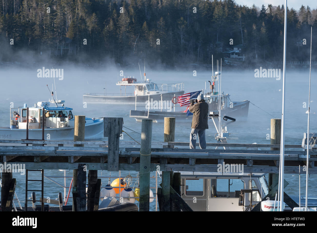 Sea smoke rises from the surface and surrounds lobster boats with ...