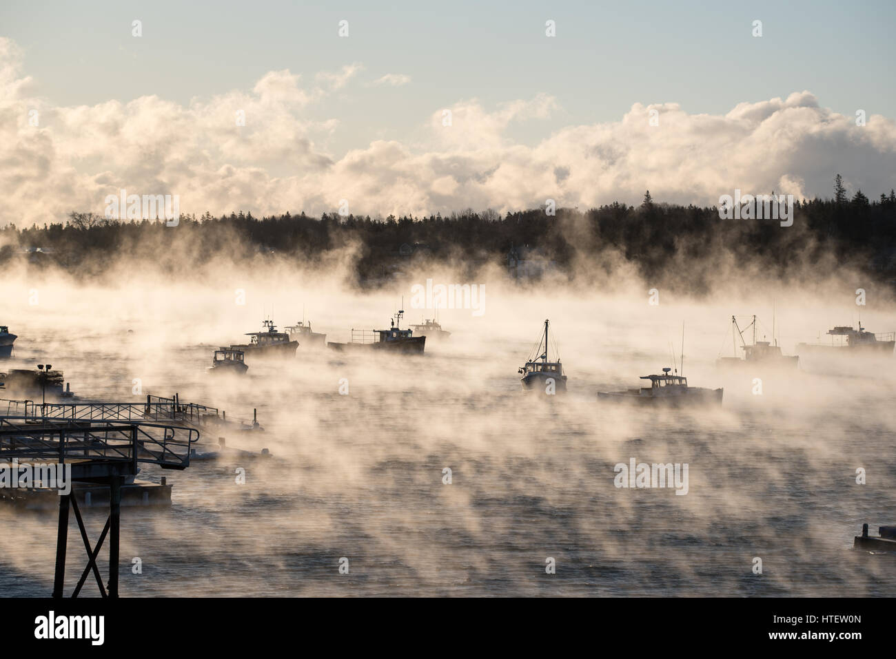 Sea smoke rises from the surface and surrounds lobster boats with ...