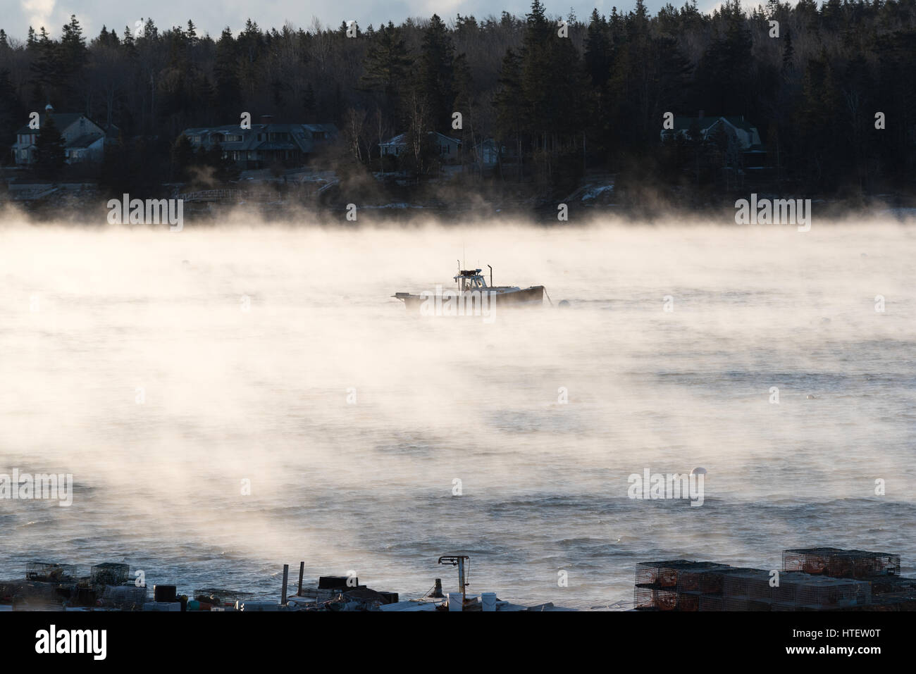 Sea smoke rises from the surface and surrounds lobster boats with ...
